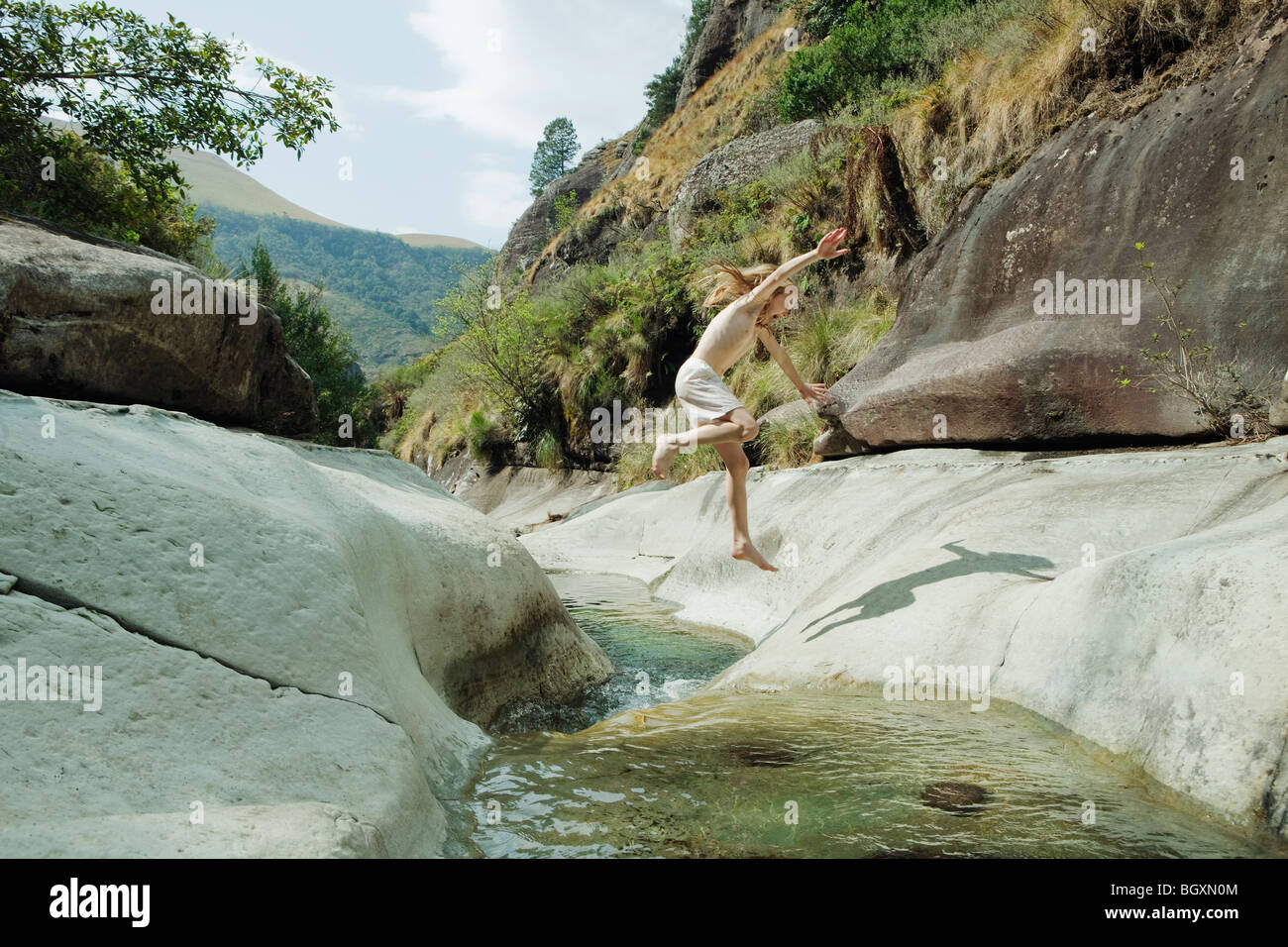 Girl jumping over stream Stock Photo - Alamy