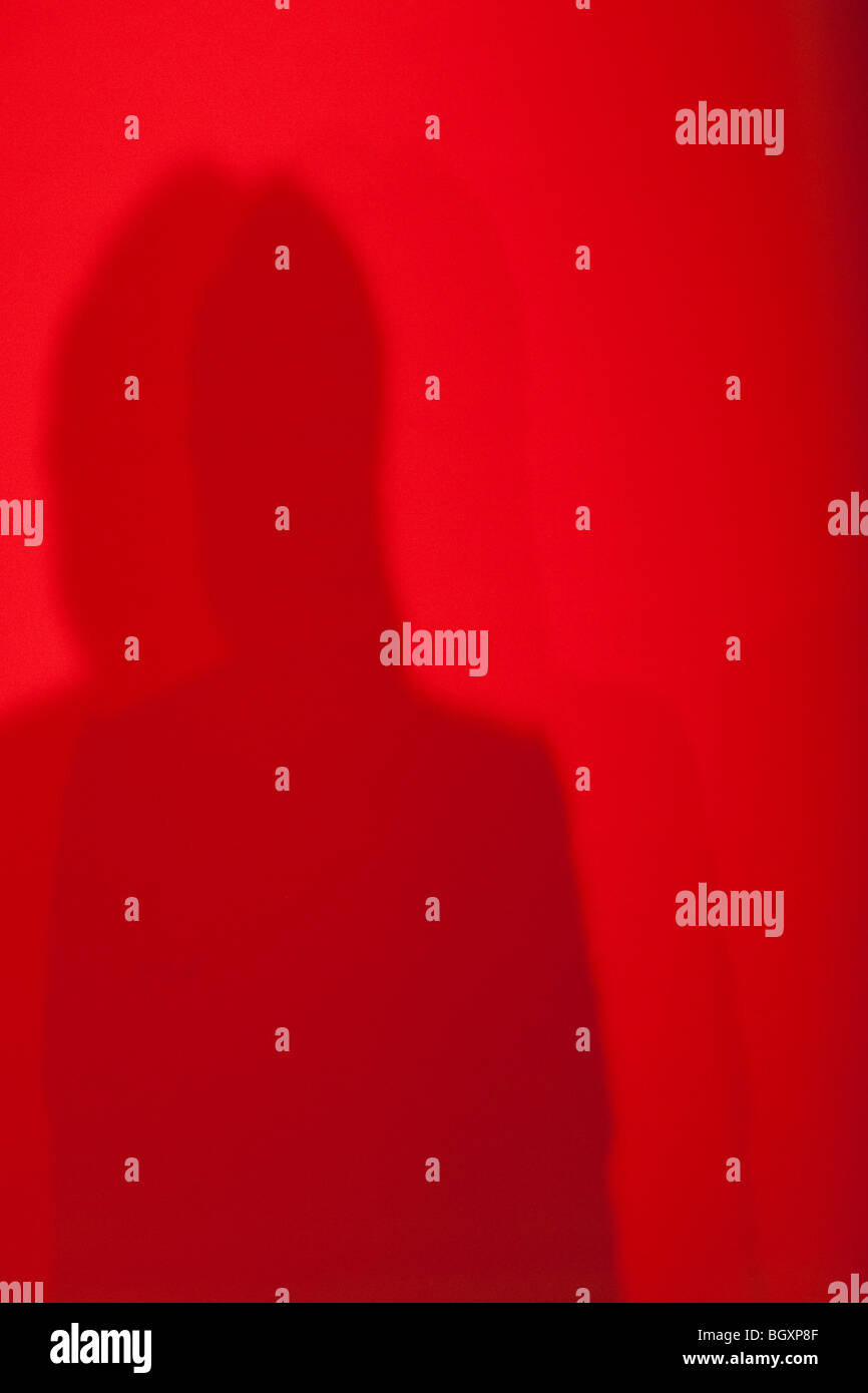 Shadow of figure human, speaker, against a red backdrop, at a ...