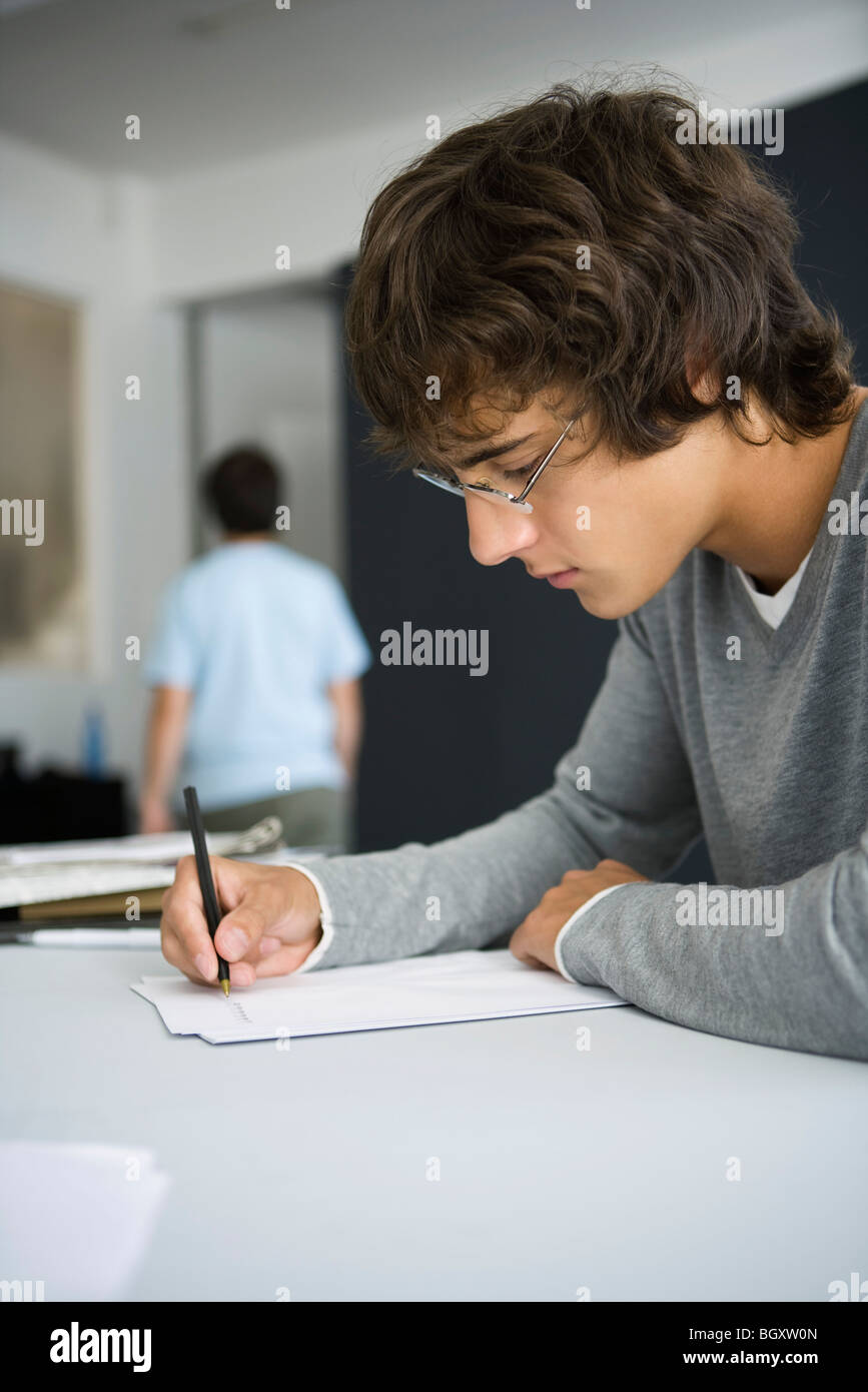 College student writing at desk in classroom Stock Photo - Alamy