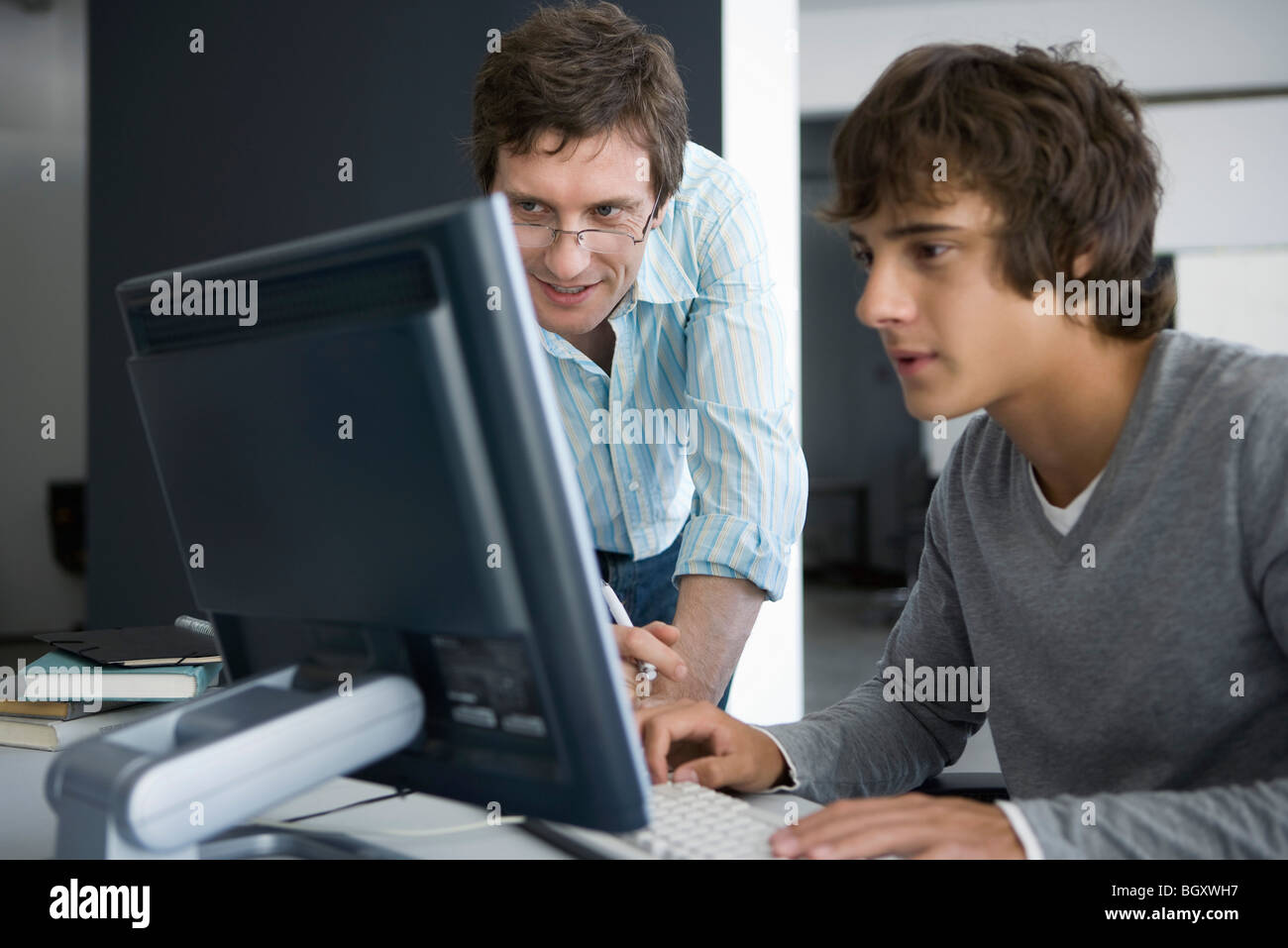 Teacher smiling, reviewing student's work on computer Stock Photo - Alamy