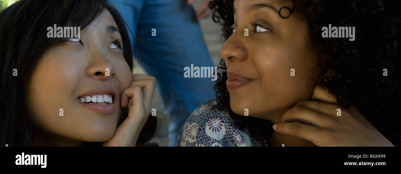 Two young women looking over shoulders at man Stock Photo - Alamy