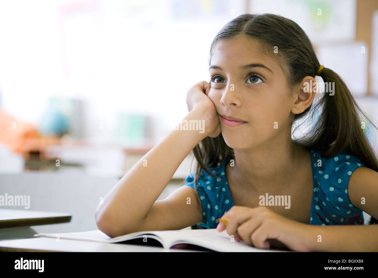Female elementary school student daydreaming in class Stock Photo - Alamy