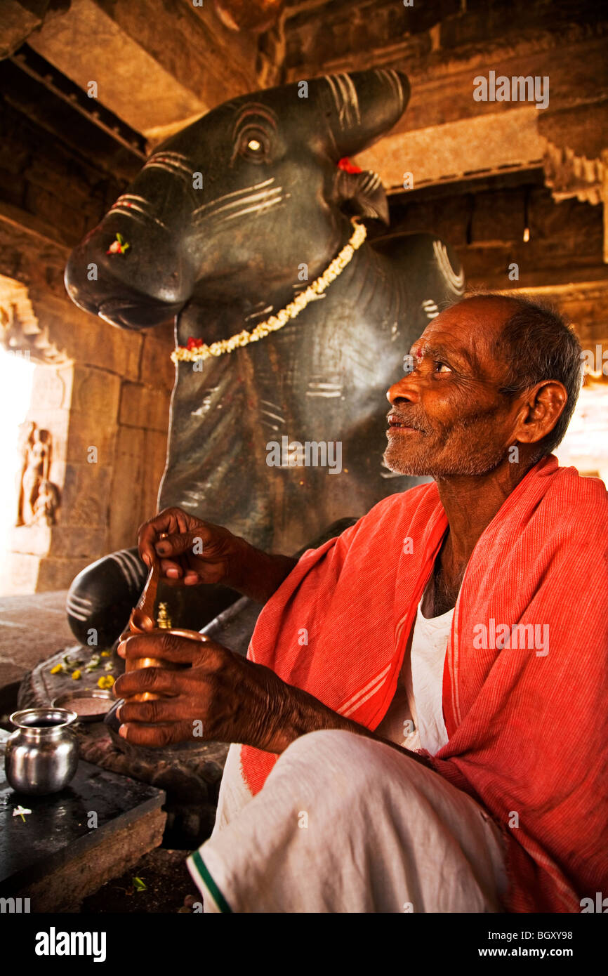 A pujari (priest) at a Nandi statue, the vehicle of Shiva, at ...