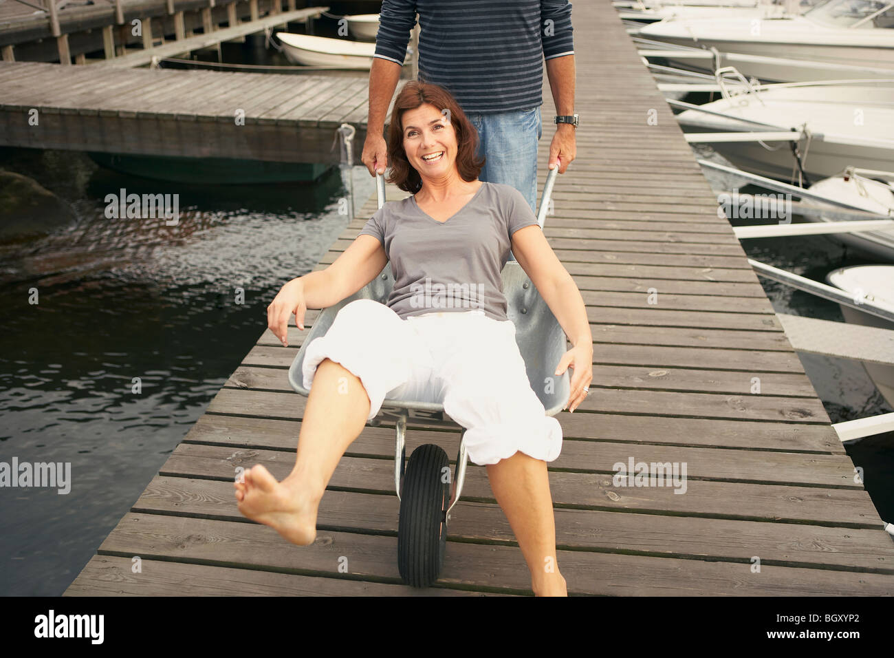 Middle aged woman pushed in wheel barrow Stock Photo - Alamy