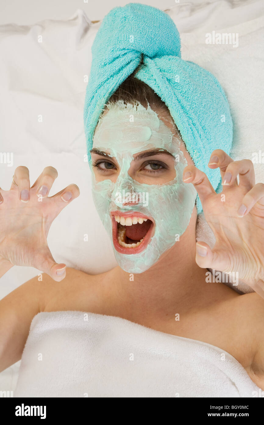 Young Caucasian woman acting silly when receiving a facial at a spa ...