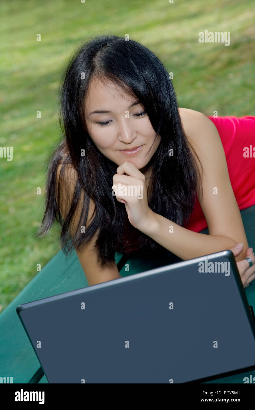 Beautiful Asian student studying using a computer at a park Stock Photo ...