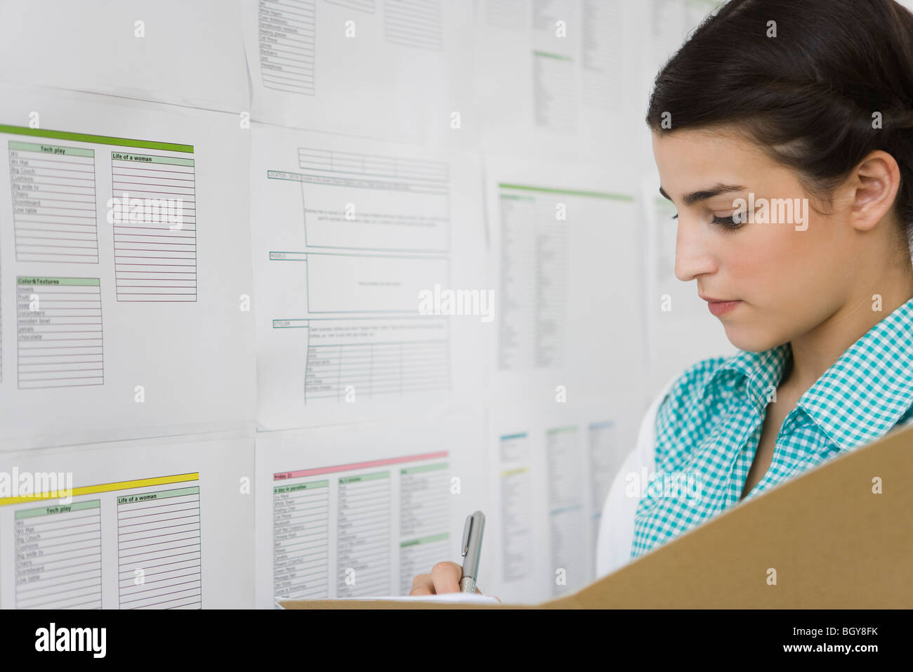Female college student writing down information posted on bulletin ...