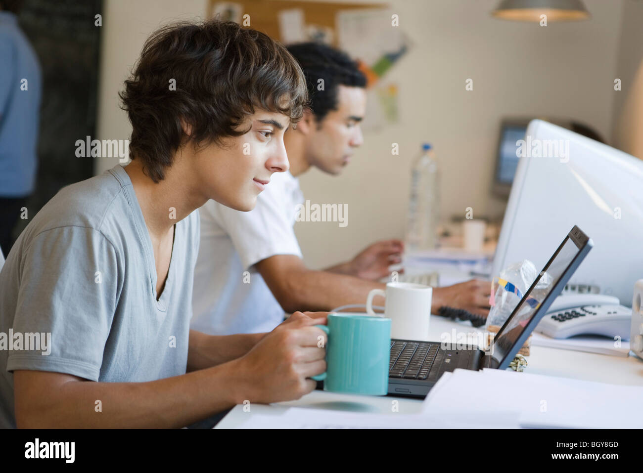 College student using laptop computer, cup of coffee in hand Stock ...