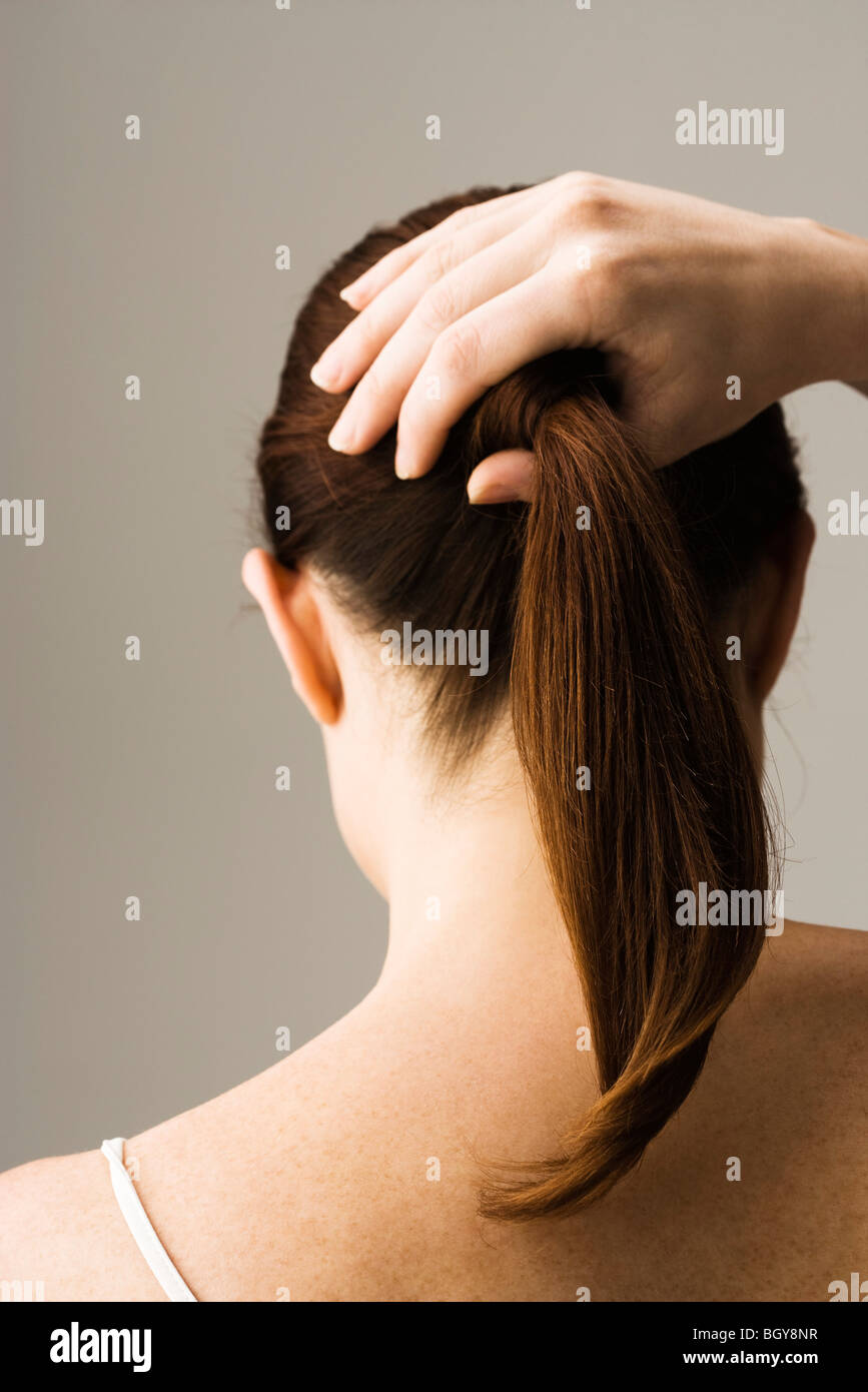 Woman styling hair, rear view Stock Photo - Alamy