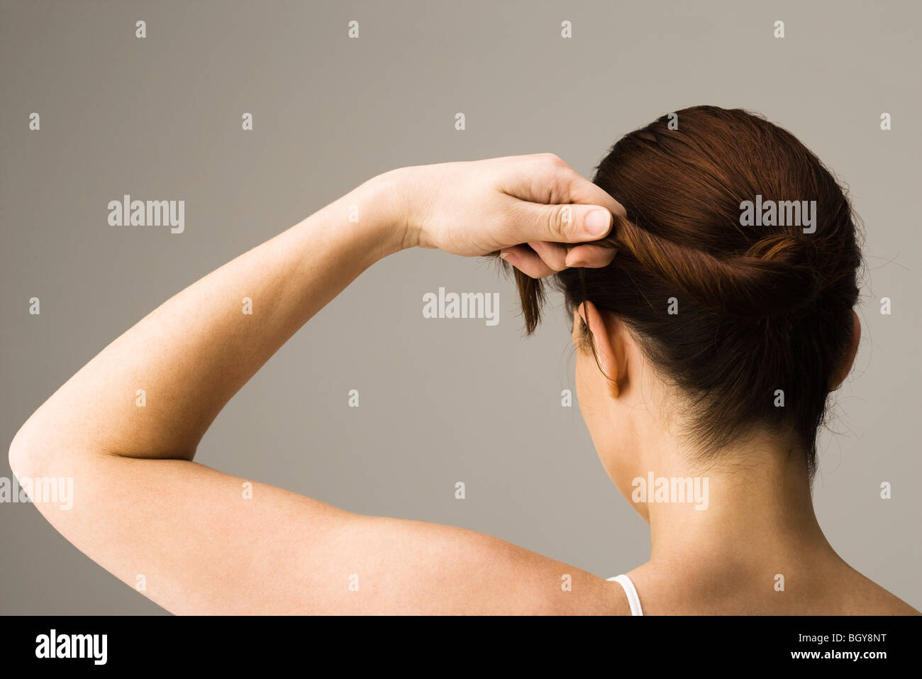 Woman styling hair, rear view Stock Photo - Alamy