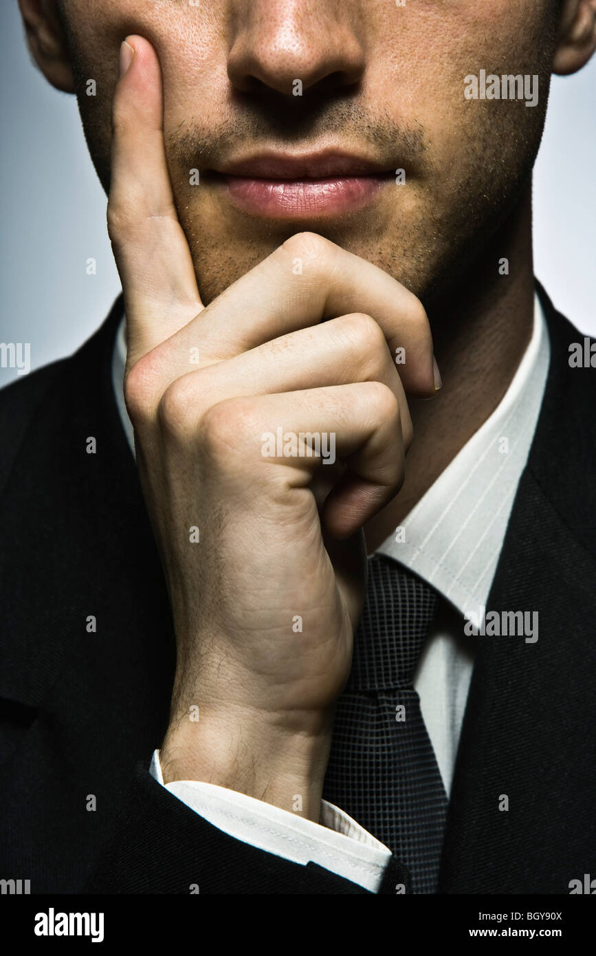 Businessman with hand under chin, portrait Stock Photo - Alamy