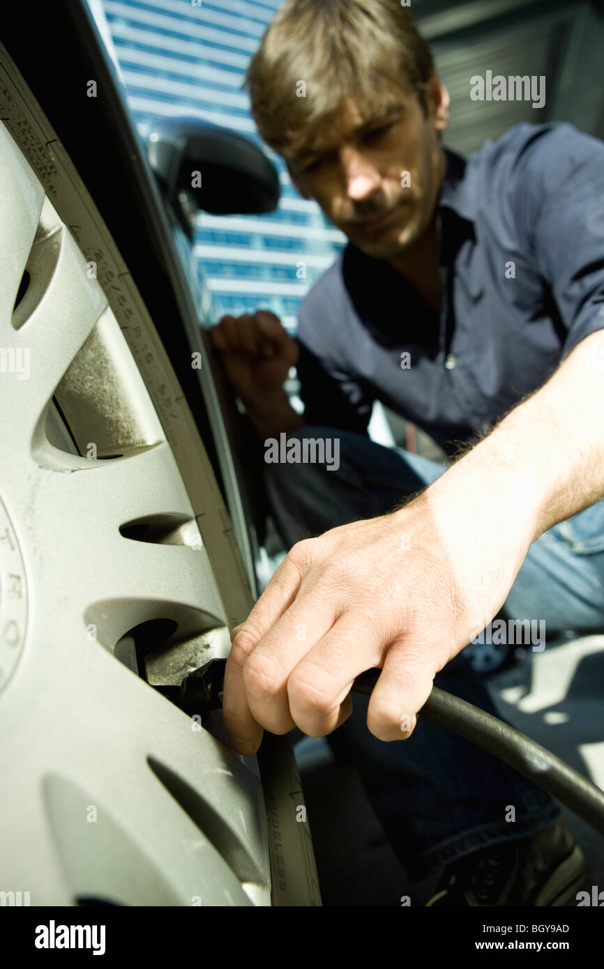 Man inflating vehicle tire using air pump hose Stock Photo - Alamy