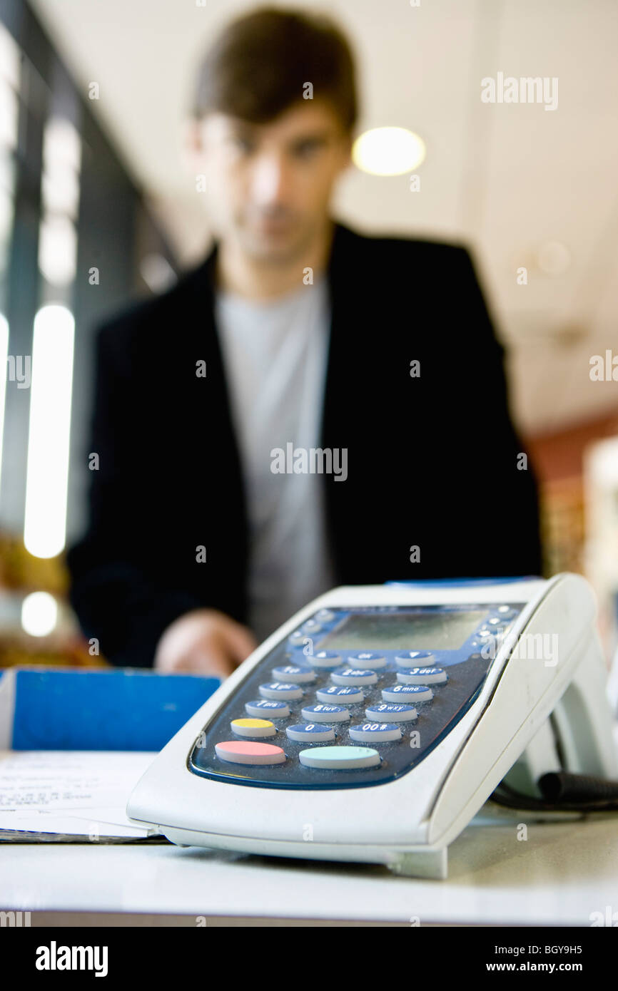 Credit card reader on checkout counter, customer in background Stock ...