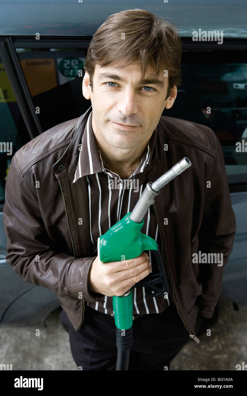 Man at gas station holding gas nozzle Stock Photo - Alamy