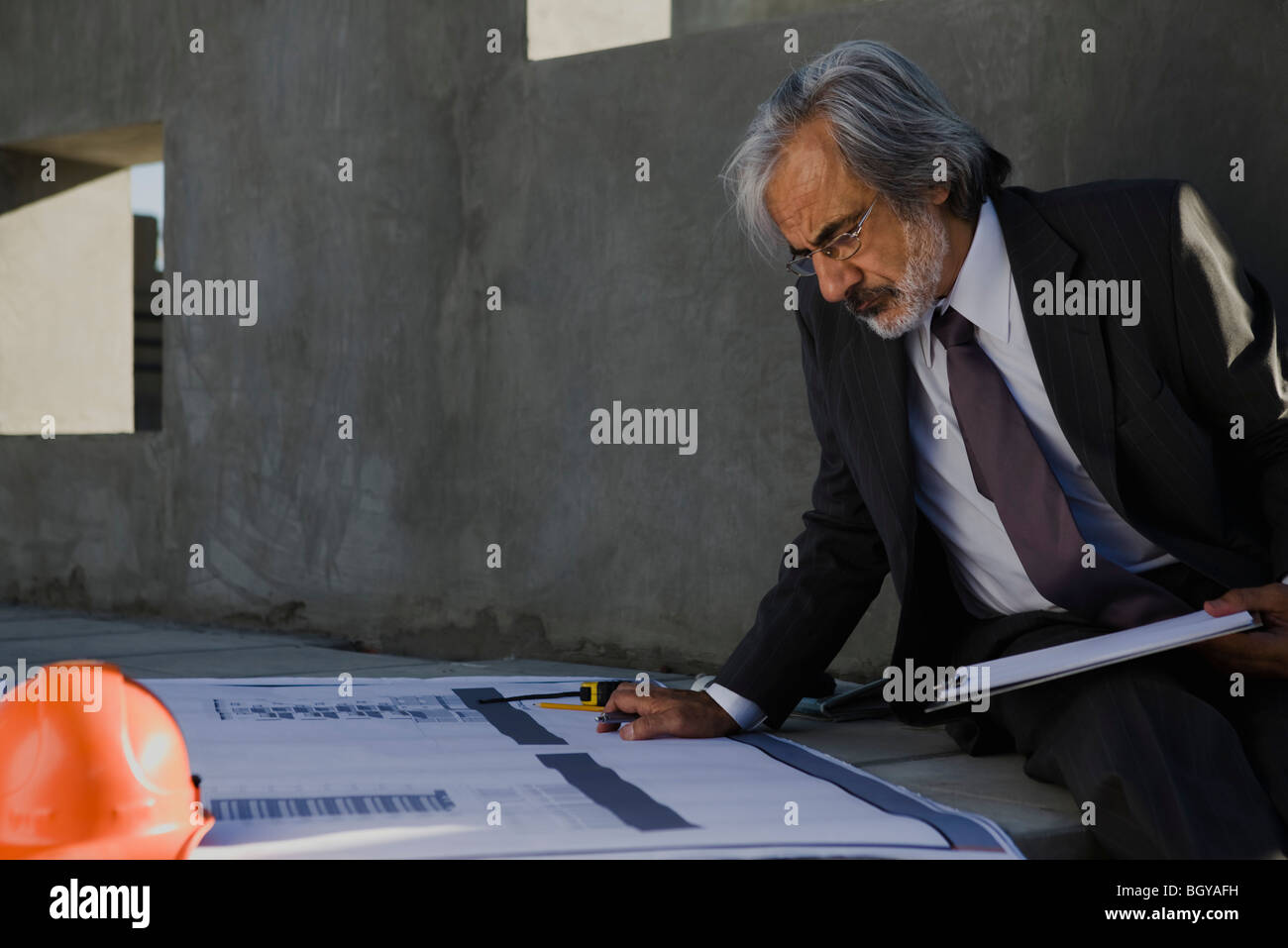 Architect studying blueprint at construction site Stock Photo - Alamy
