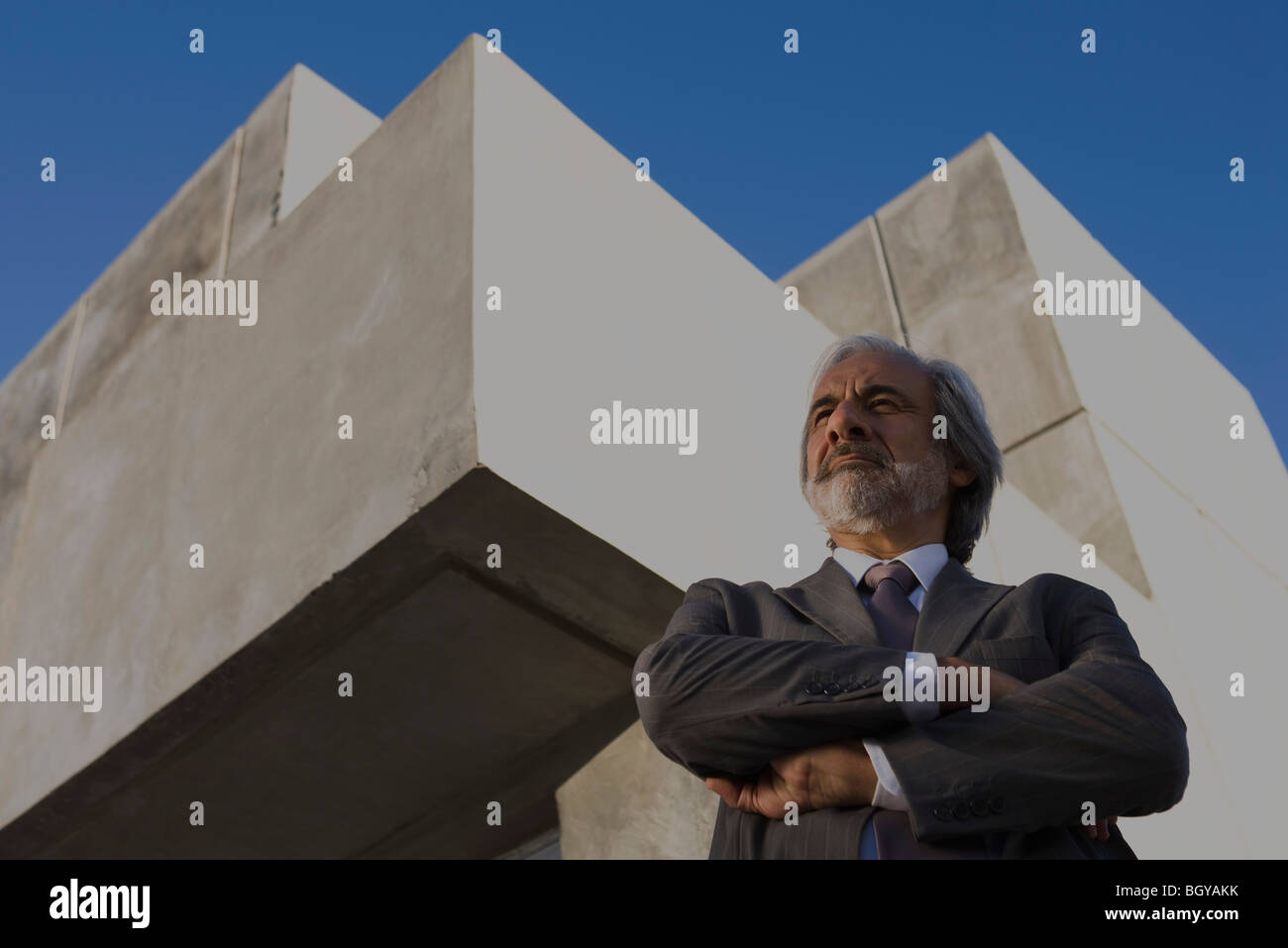 Architect standing in front of building with arms folded, looking away ...