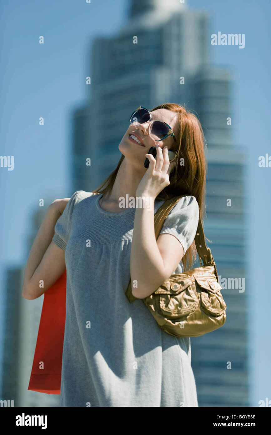 Young woman carrying shopping bags, talking on cell phone Stock Photo ...