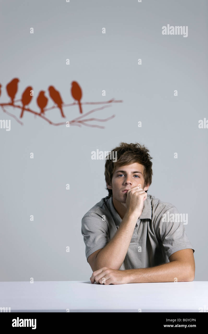 Young man sitting, leaning on elbow, portrait Stock Photo - Alamy