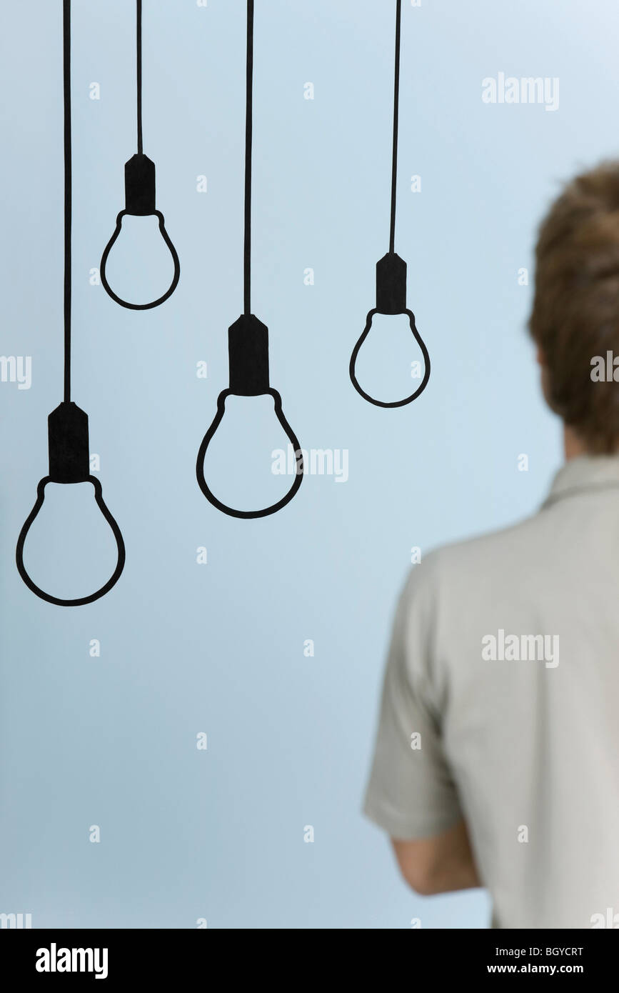 Man looking at light bulb graphic on wall, rear view Stock Photo - Alamy