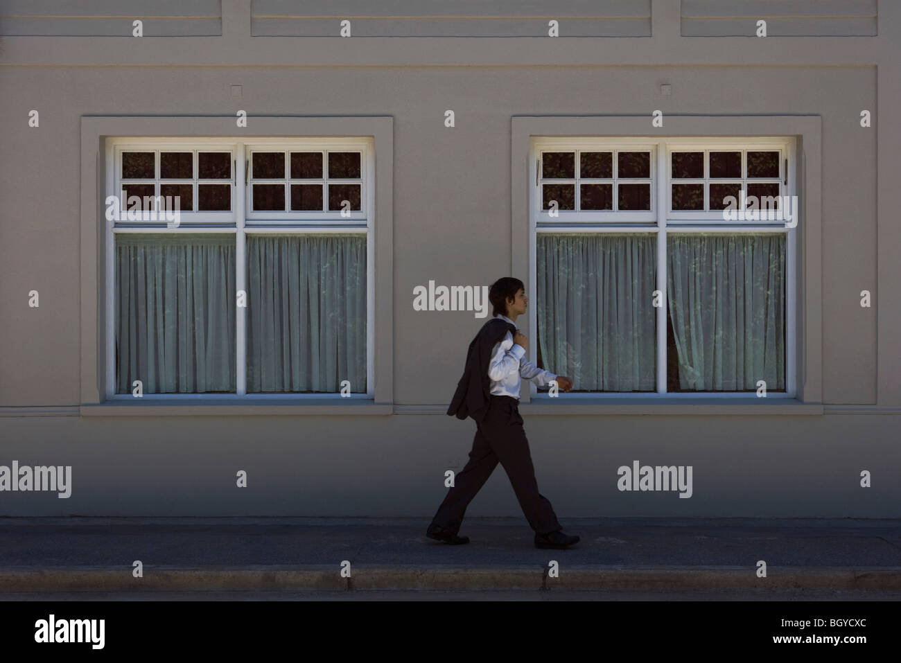 Young man in business attire walking on sidewalk, side view Stock Photo ...