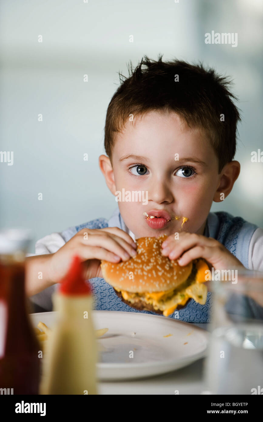 Little boy eating cheeseburger Stock Photo - Alamy