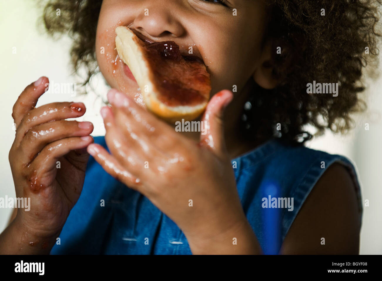 Little girl eating snack, hands and face covered in jam Stock Photo - Alamy