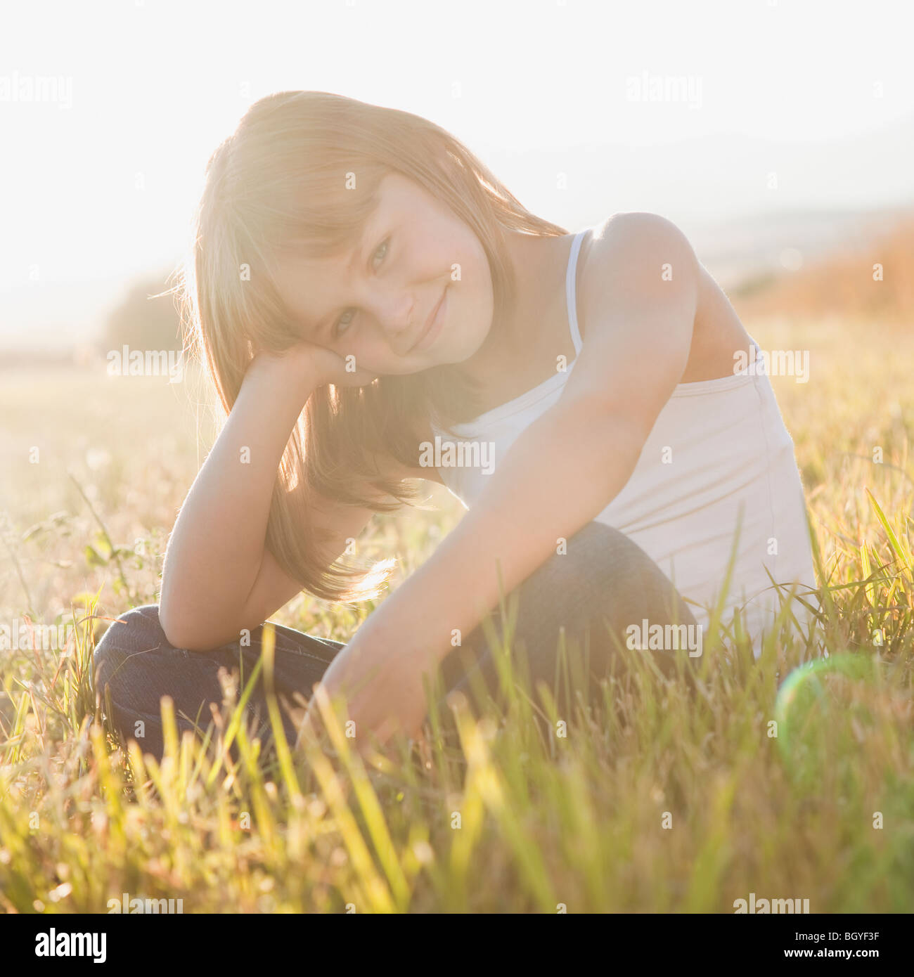 Portrait of young girl sitting in field Stock Photo - Alamy