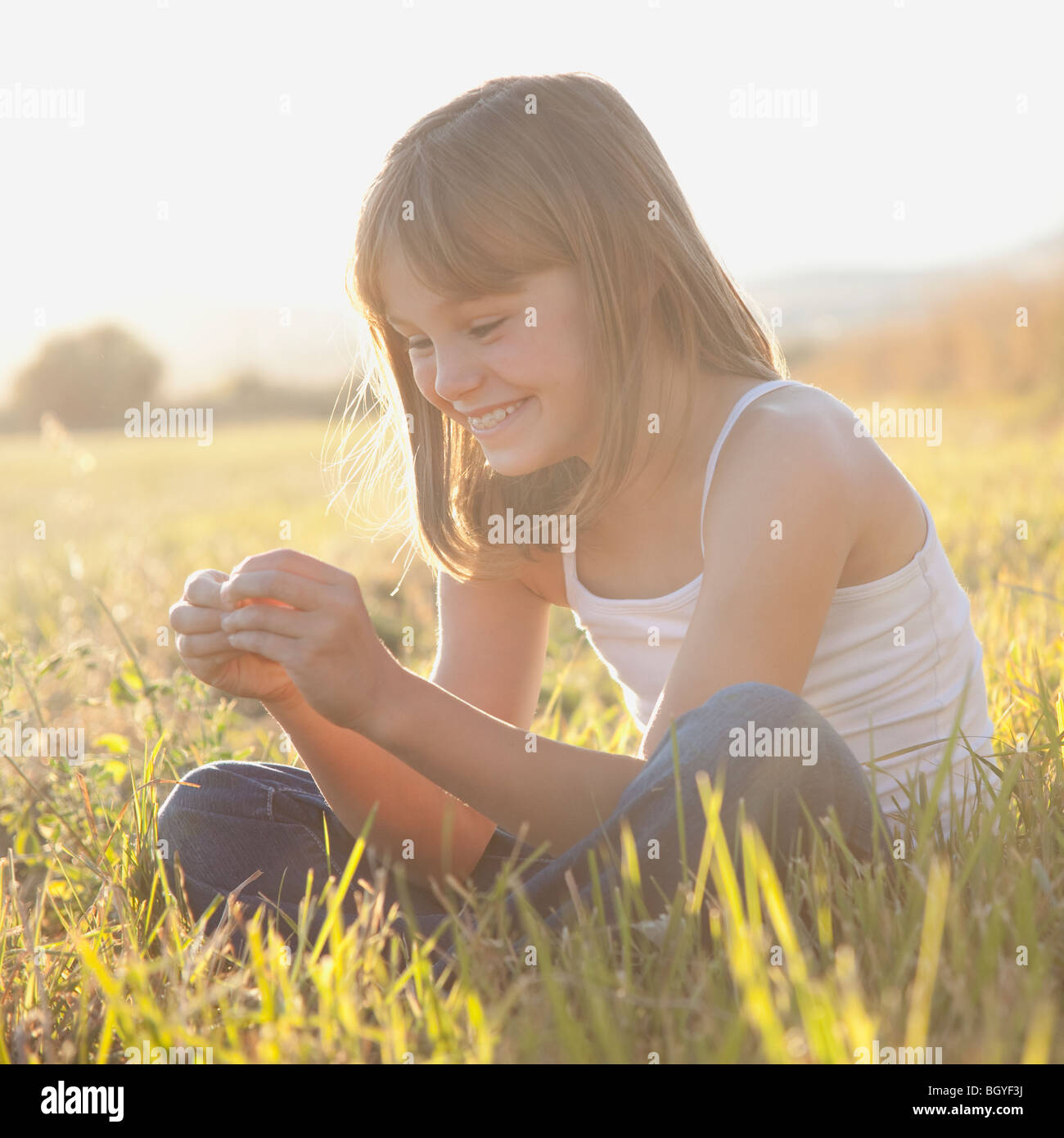 Portrait of young girl sitting in field Stock Photo - Alamy