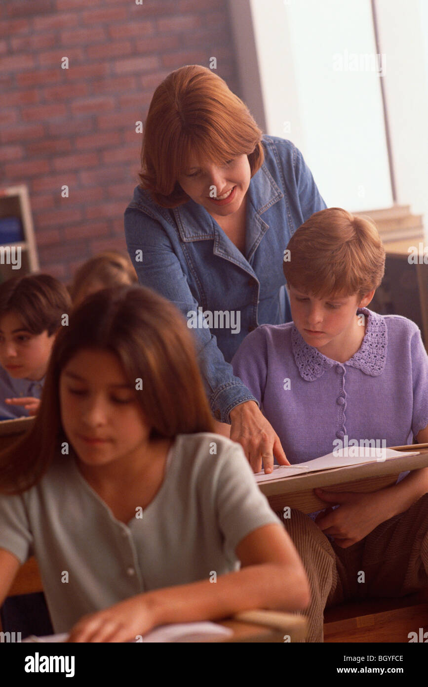 Teacher helping student in classroom Stock Photo - Alamy
