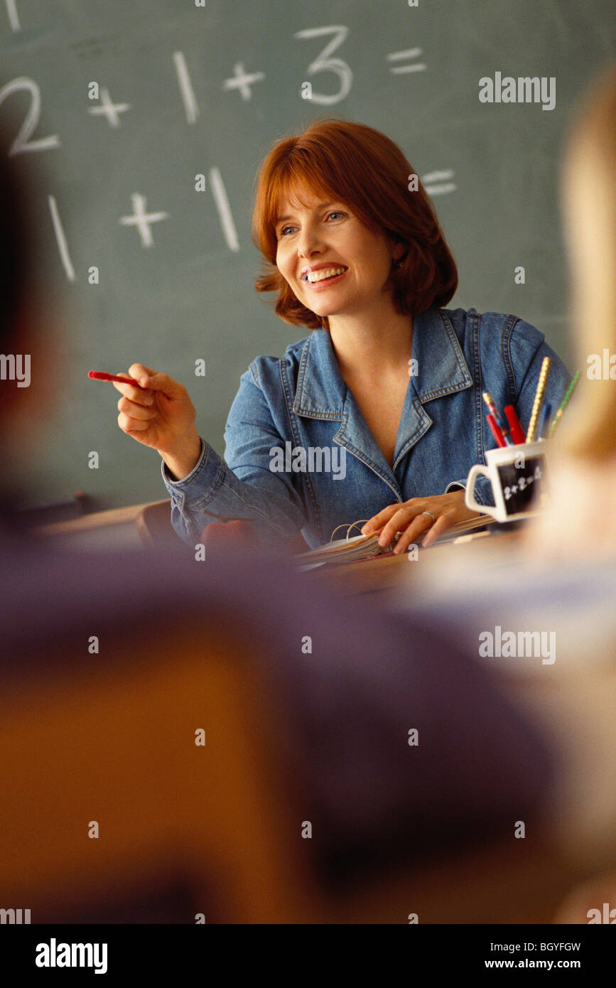 Teacher sitting at desk in classroom Stock Photo - Alamy