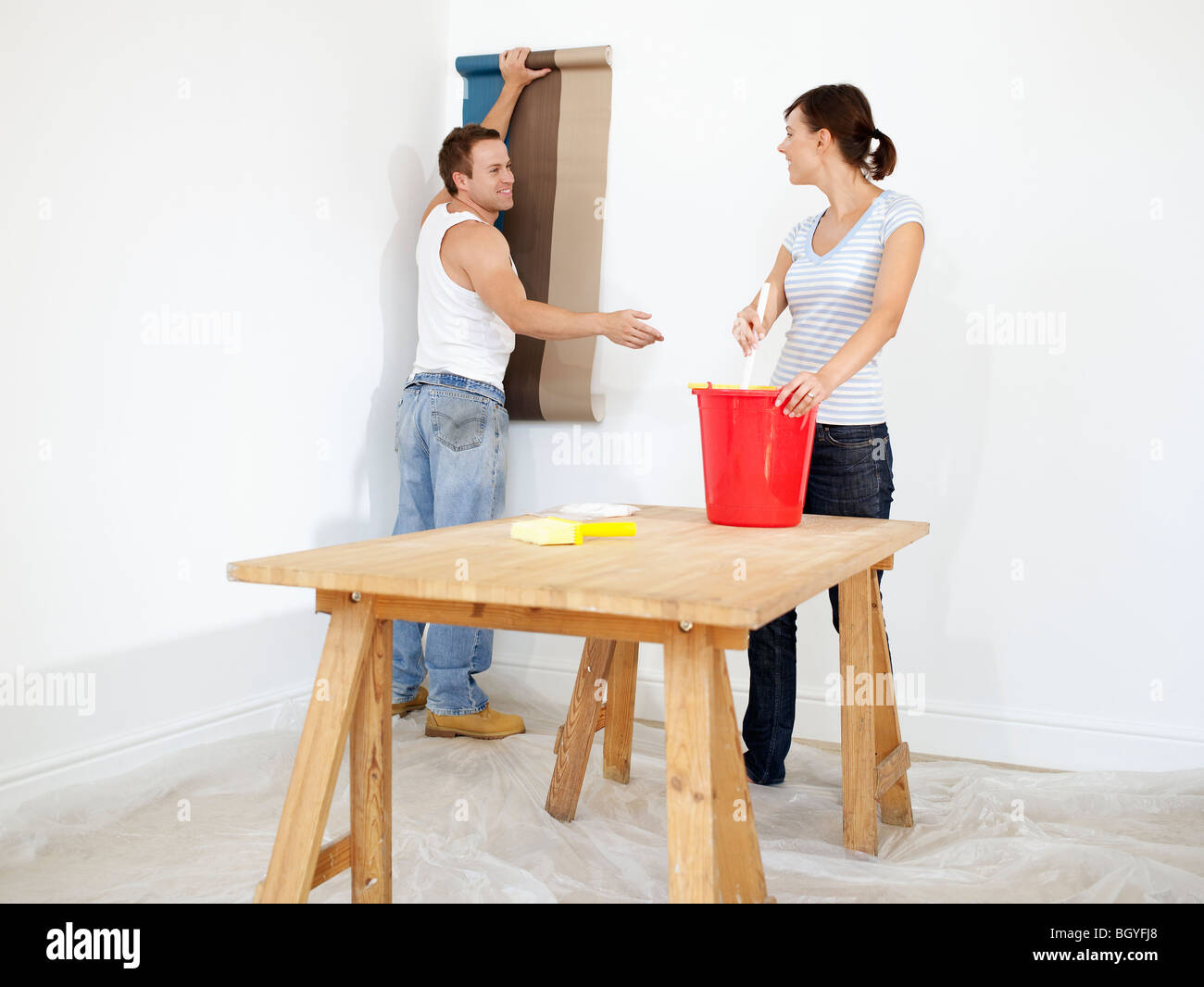 Couple putting up wallpaper Stock Photo - Alamy