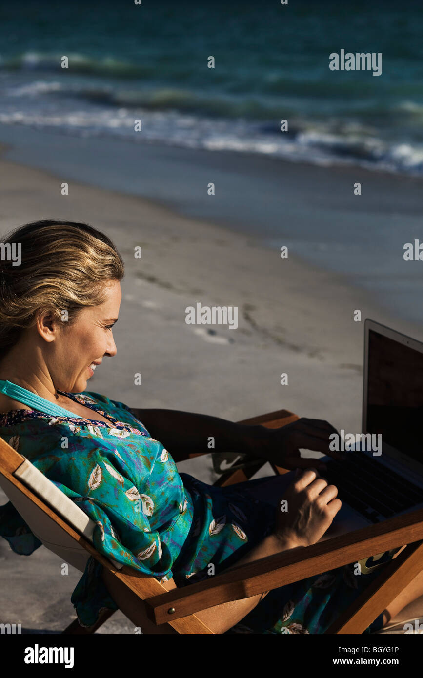 Woman using laptop computer at beach Stock Photo - Alamy