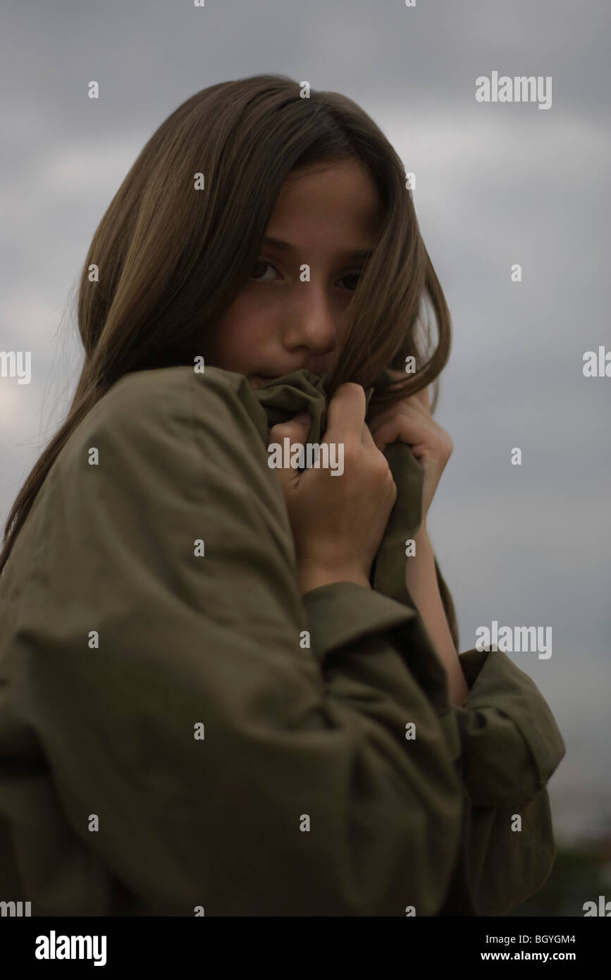 Female shielding face from cold behind coat lapel, portrait Stock Photo ...