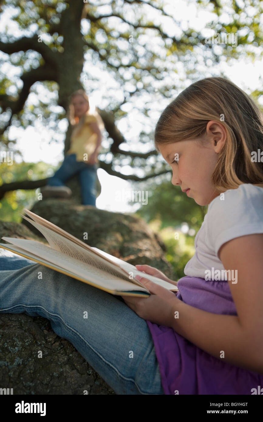 Girl reading book in tree Stock Photo - Alamy