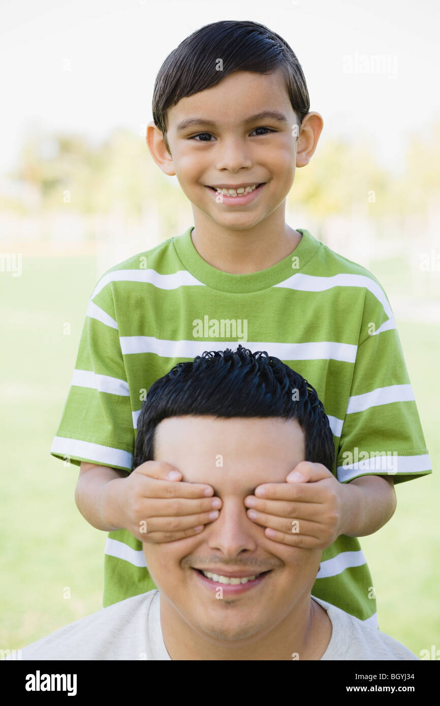 Boy covering man's eyes Stock Photo - Alamy