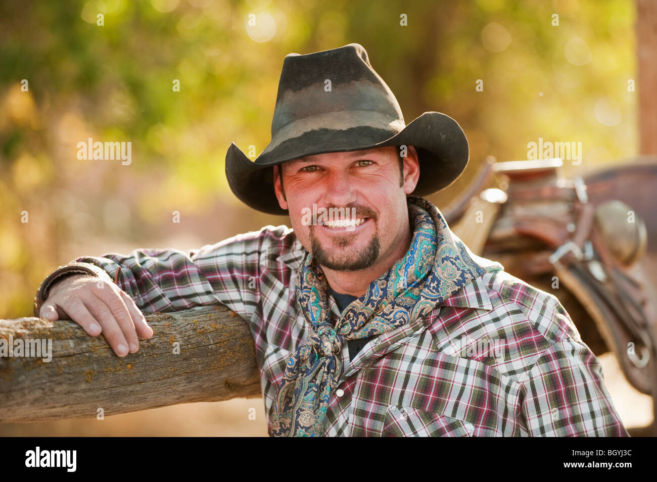 Cowboy leaning on fence Stock Photo - Alamy