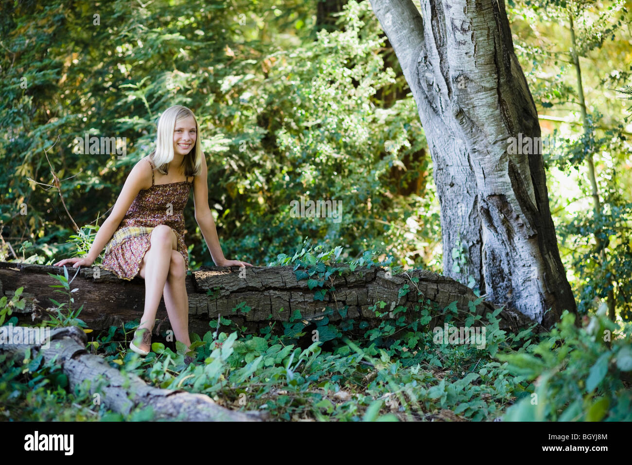Young woman sitting on log Stock Photo - Alamy