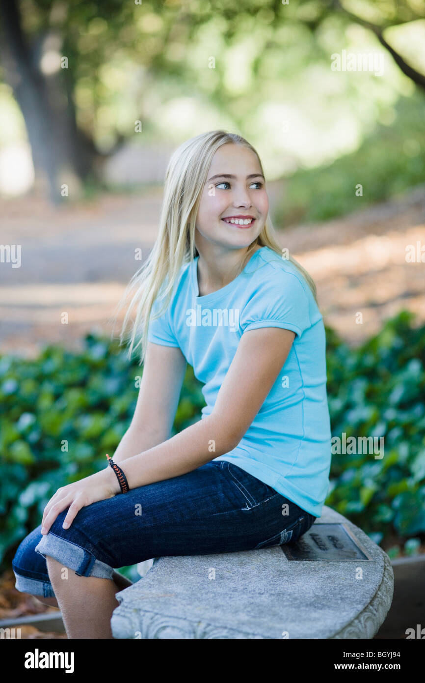Young girl sitting on bench Stock Photo - Alamy