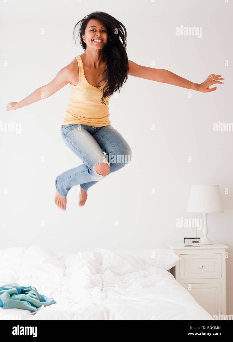 Woman jumping on bed Stock Photo - Alamy