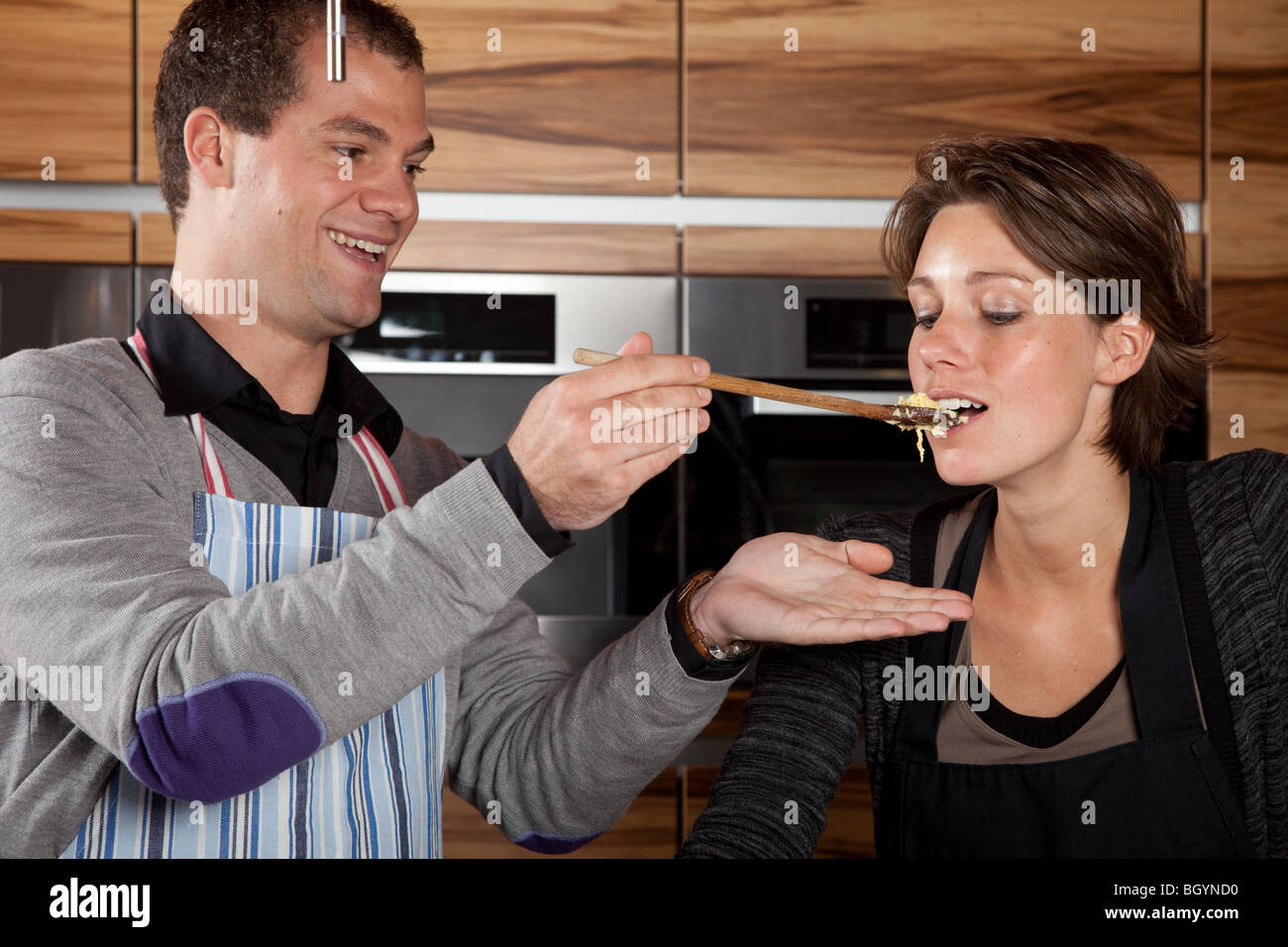 Man holding up the spoon to his girlfriend so she can taste Stock Photo ...