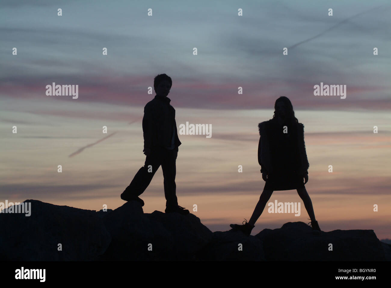 boy and girl silhouetted against sunset sky Stock Photo - Alamy