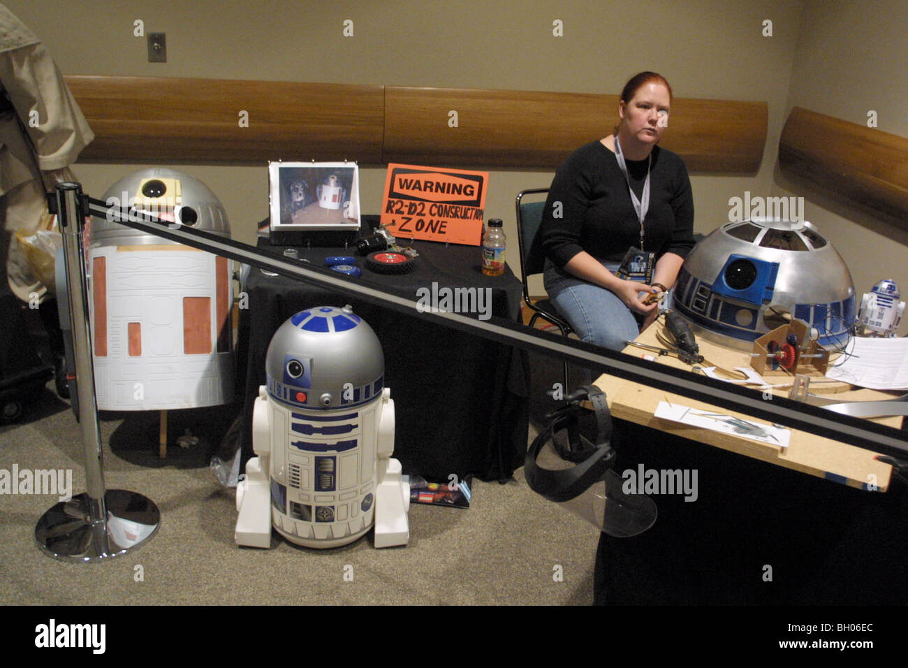 A convention attendee sits with a couple R2-D2 units at the ...