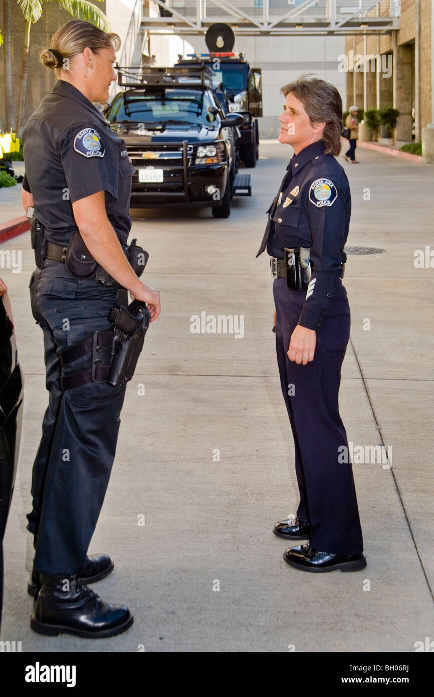 A short female police commander speaks with a tall woman officer at the ...
