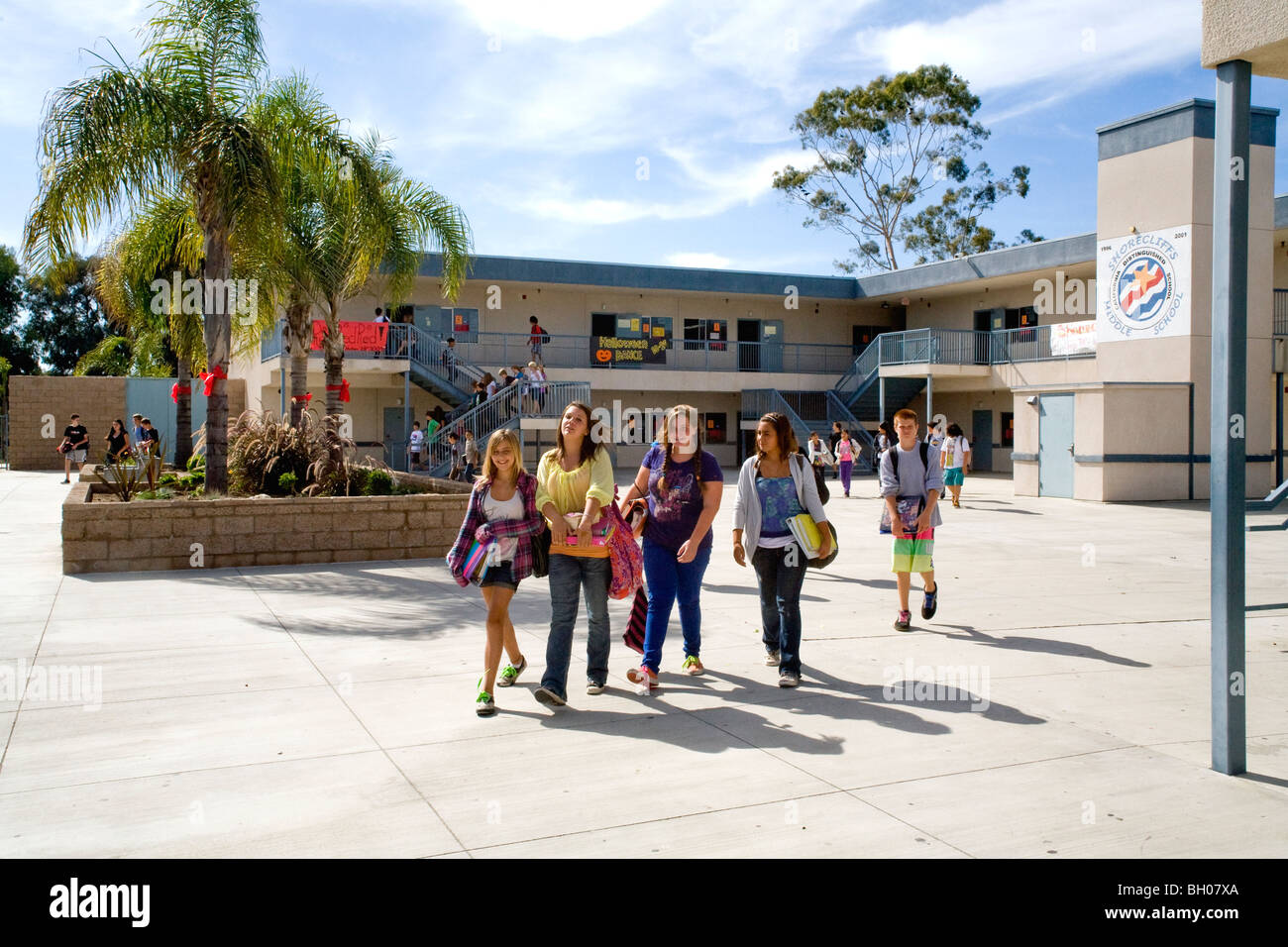 Caucasian and Hispanic middle school students cross their schoolyard in ...