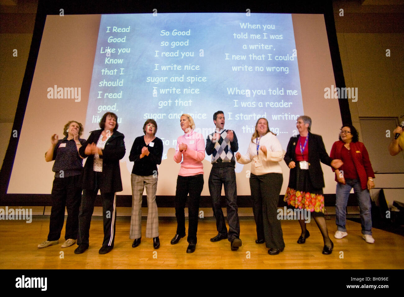 Happy high school English teachers dance on stage at the conclusion of ...