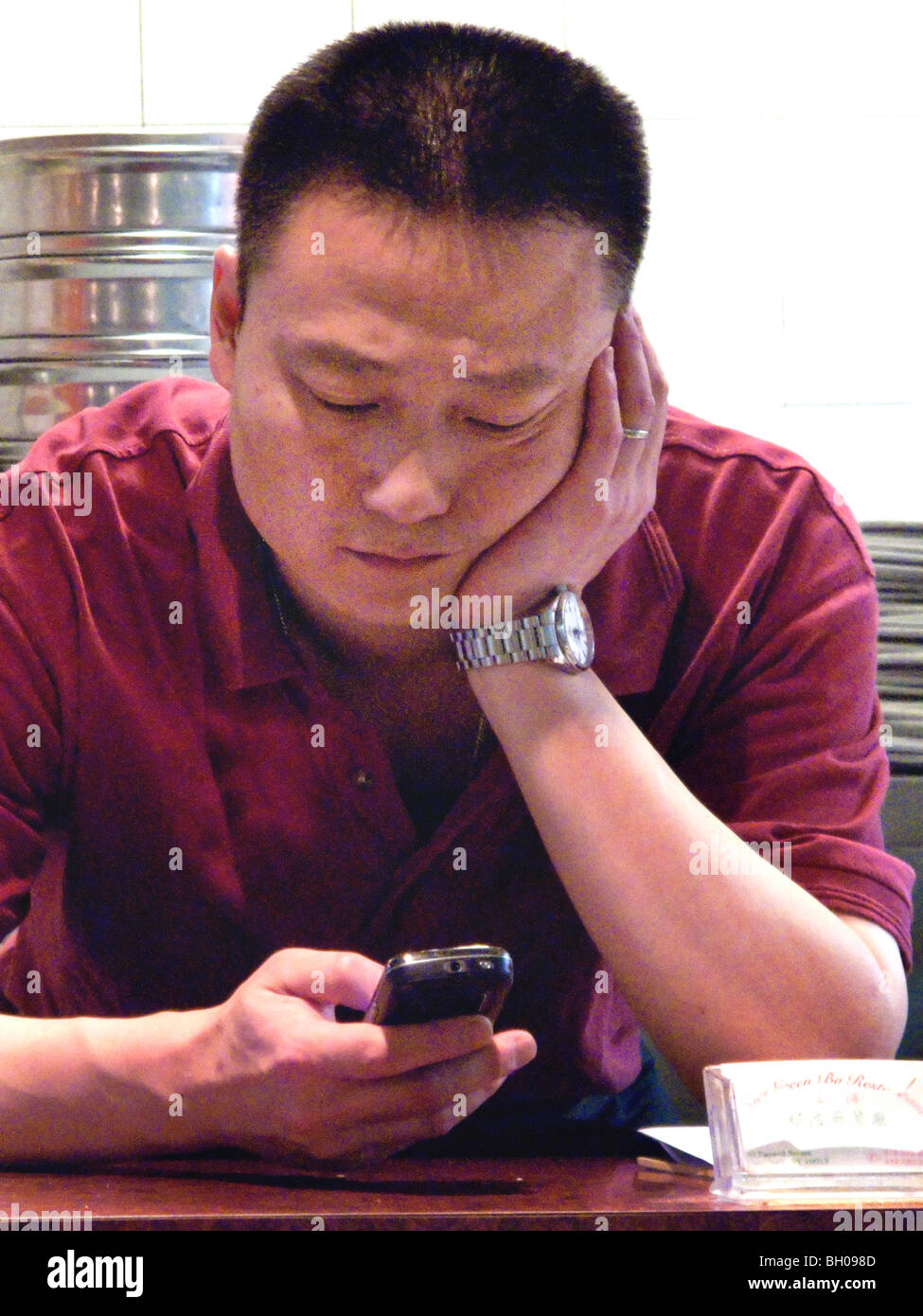 A bored Chinese waiter reads text from his cell phone at a late night ...