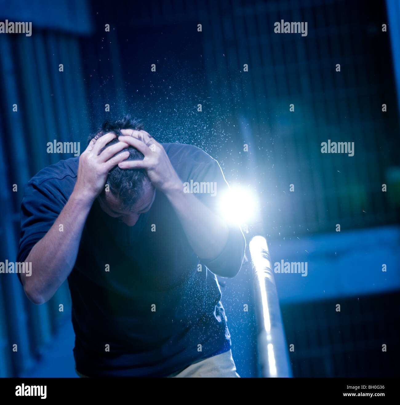 A man running water through his hair and looking stressed or anxious ...