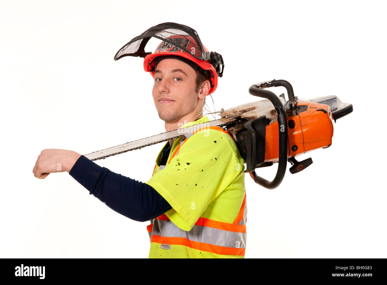 A logger carries his chainsaw over his shoulder and looks at the camera ...