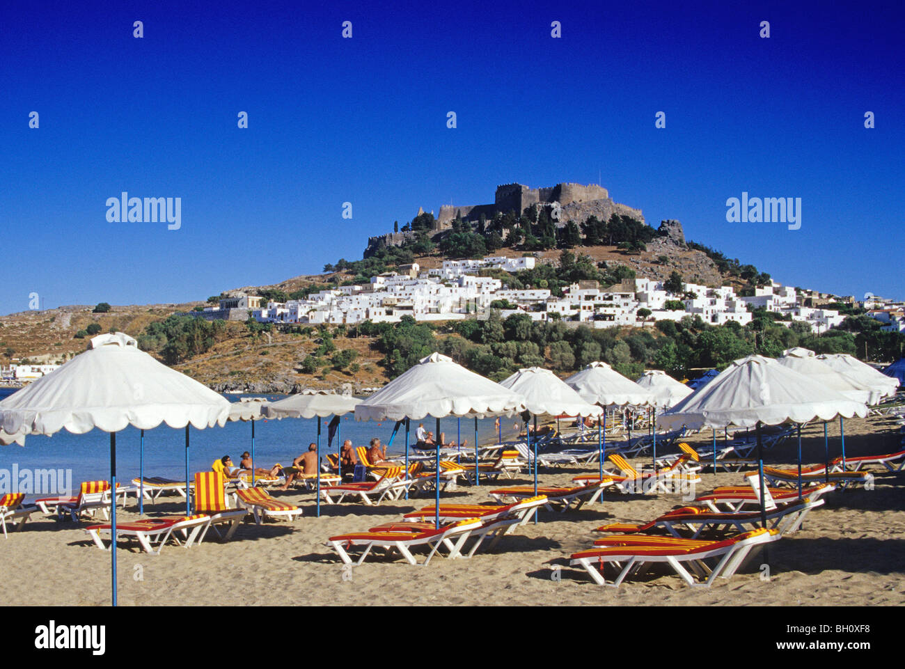 View at bay with beach, city and acropolis under blue sky, Lindos ...