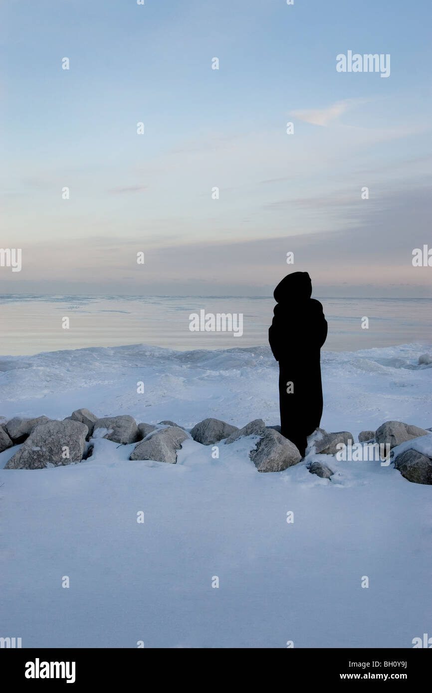 Dark figure looking out over a desolate winter shoreline Stock Photo ...